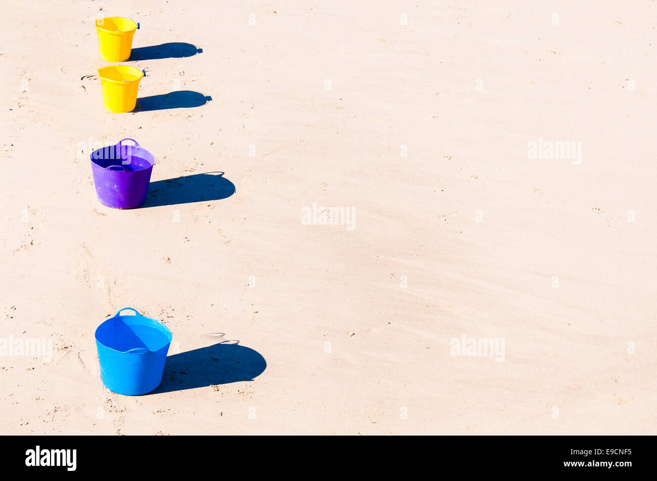 Row of colorful buckets on the beach sand Stock Photo - Alamy