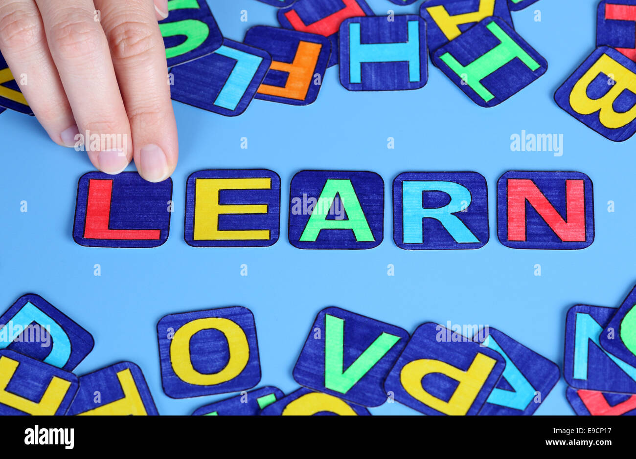 Word "Learn" spell out on a desk with woman's hand and letters. Letters ...