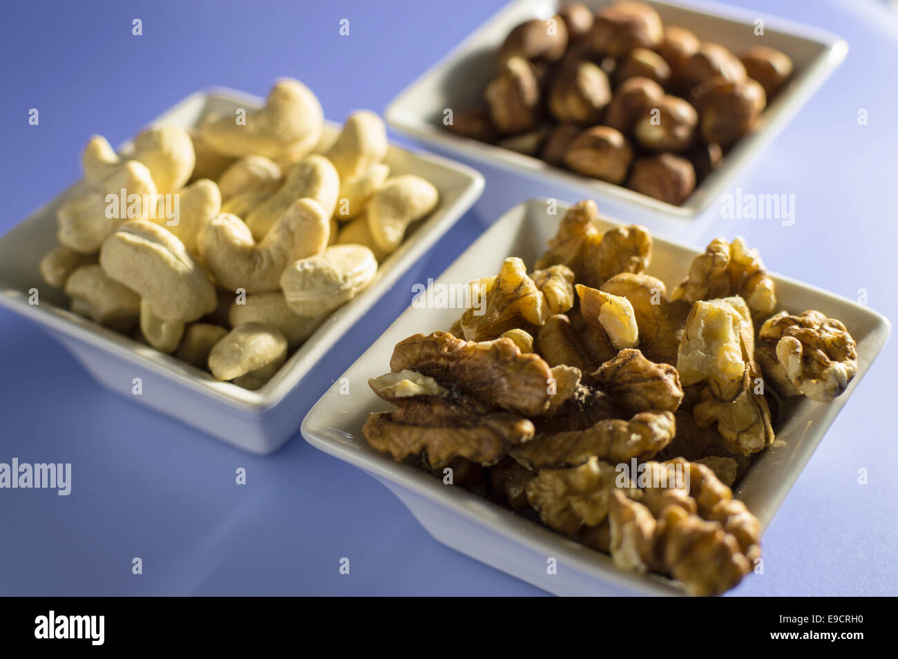 Small white snack bowls filled with a different type of nut. Cashews ...