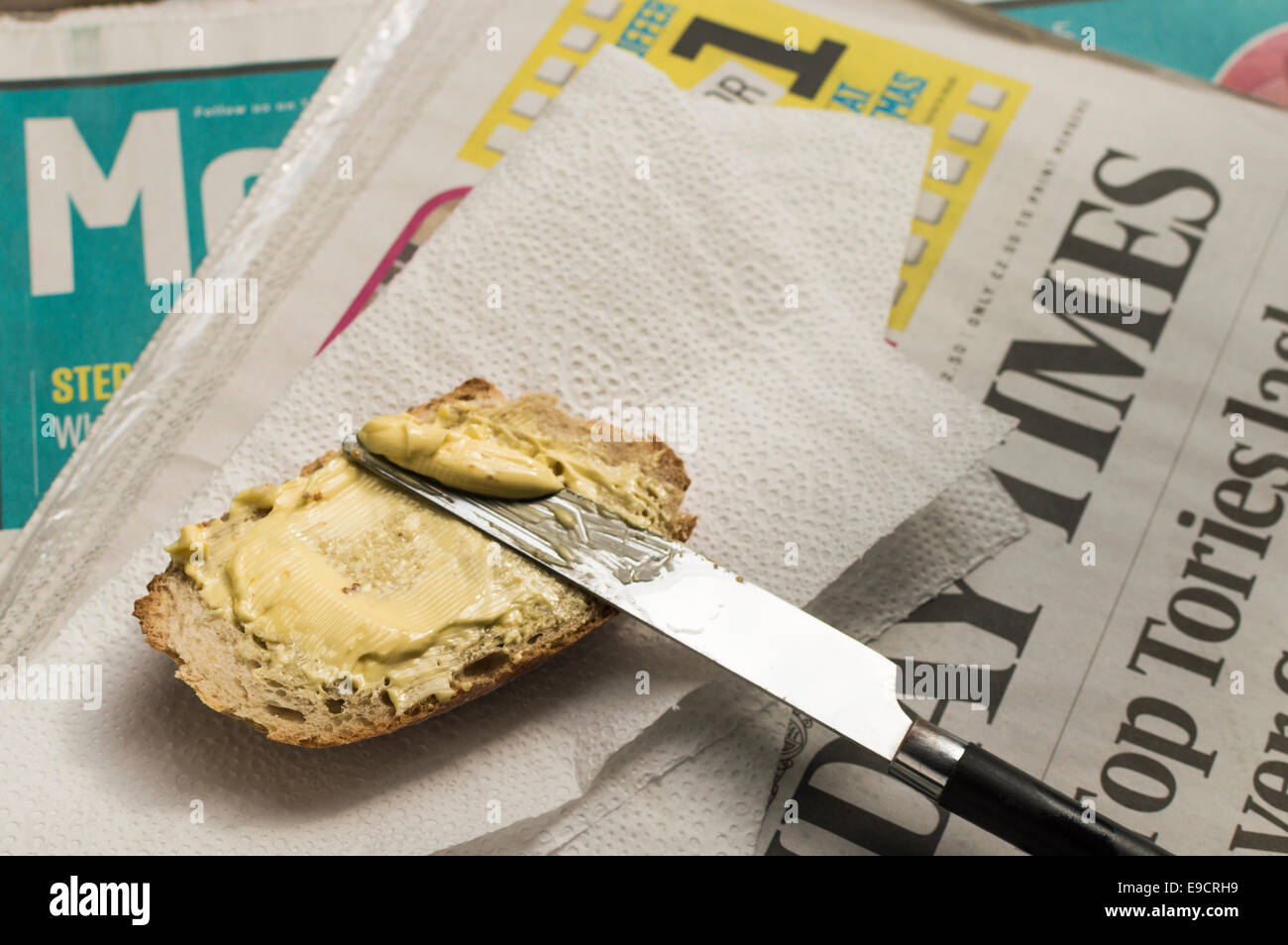 Piece of bread, slathered with butter, sitting on a kitchen towel on a ...
