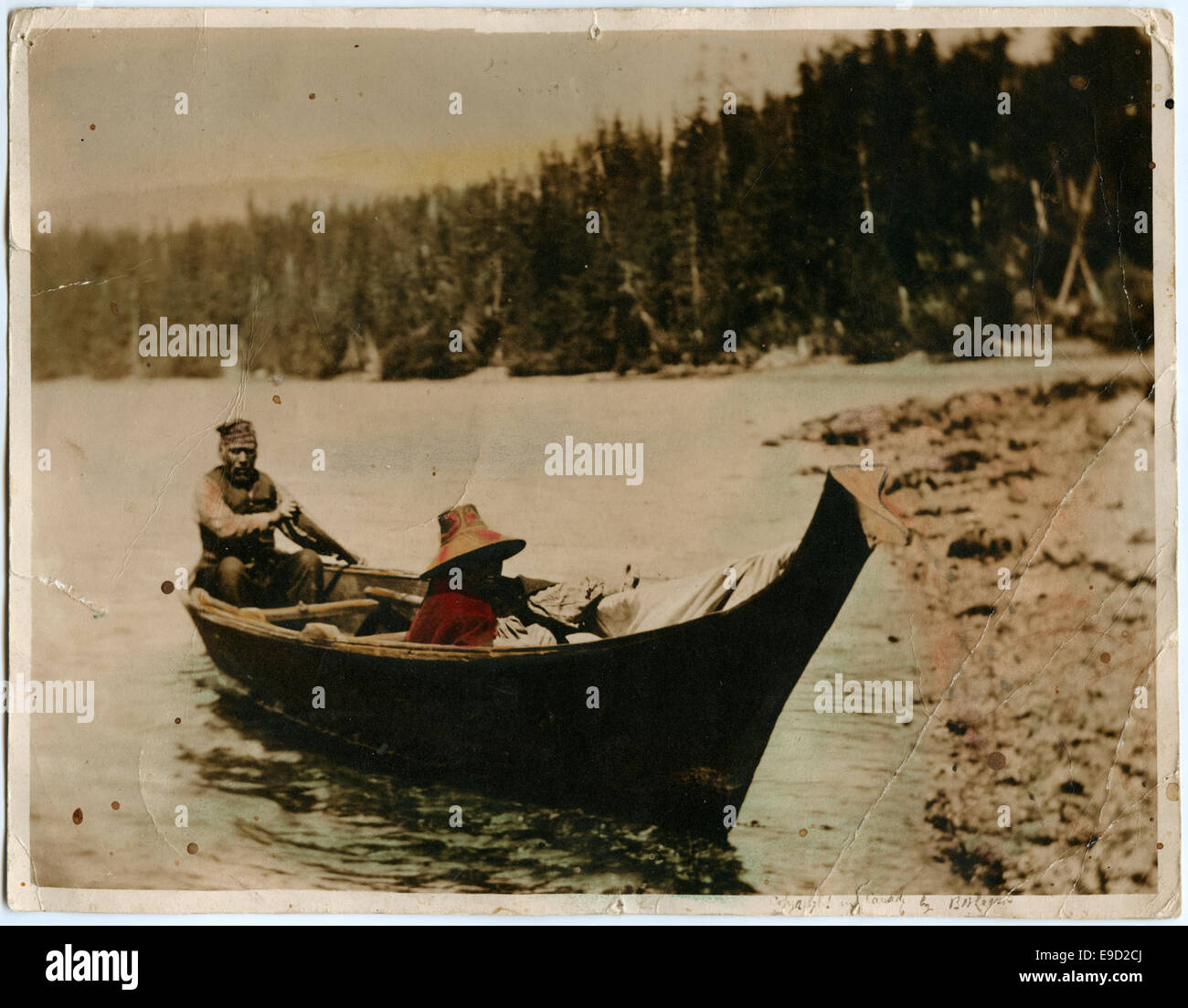 A photograph of Warcas and his wife, posed in a dugout canoe. The image ...