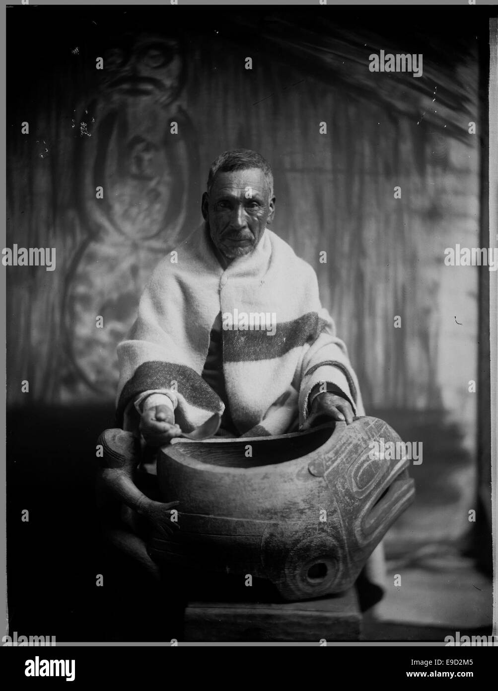 This photograph features a Quatsino man holding a carved ceremonial ...