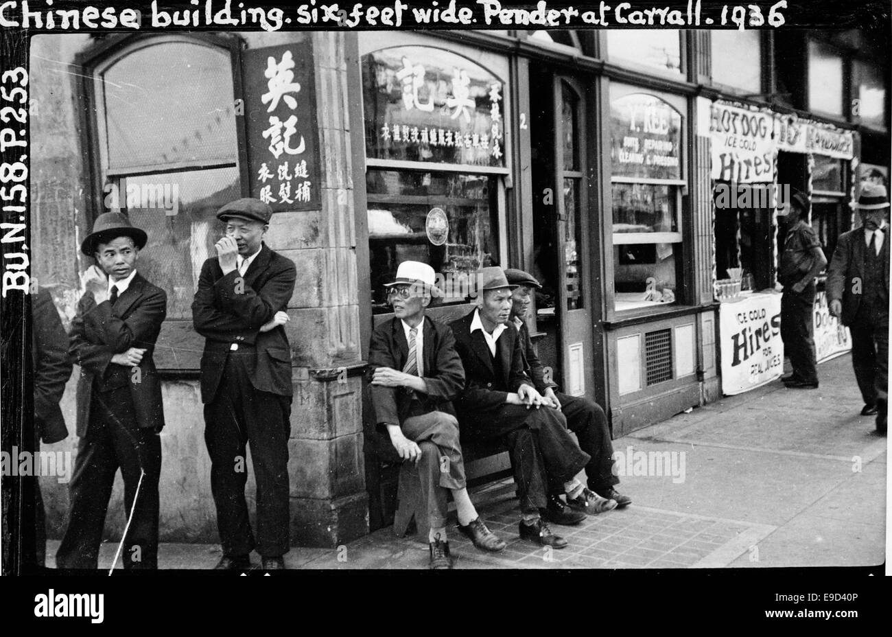 A photograph of men standing in front of the Sam Kee Building, one of ...