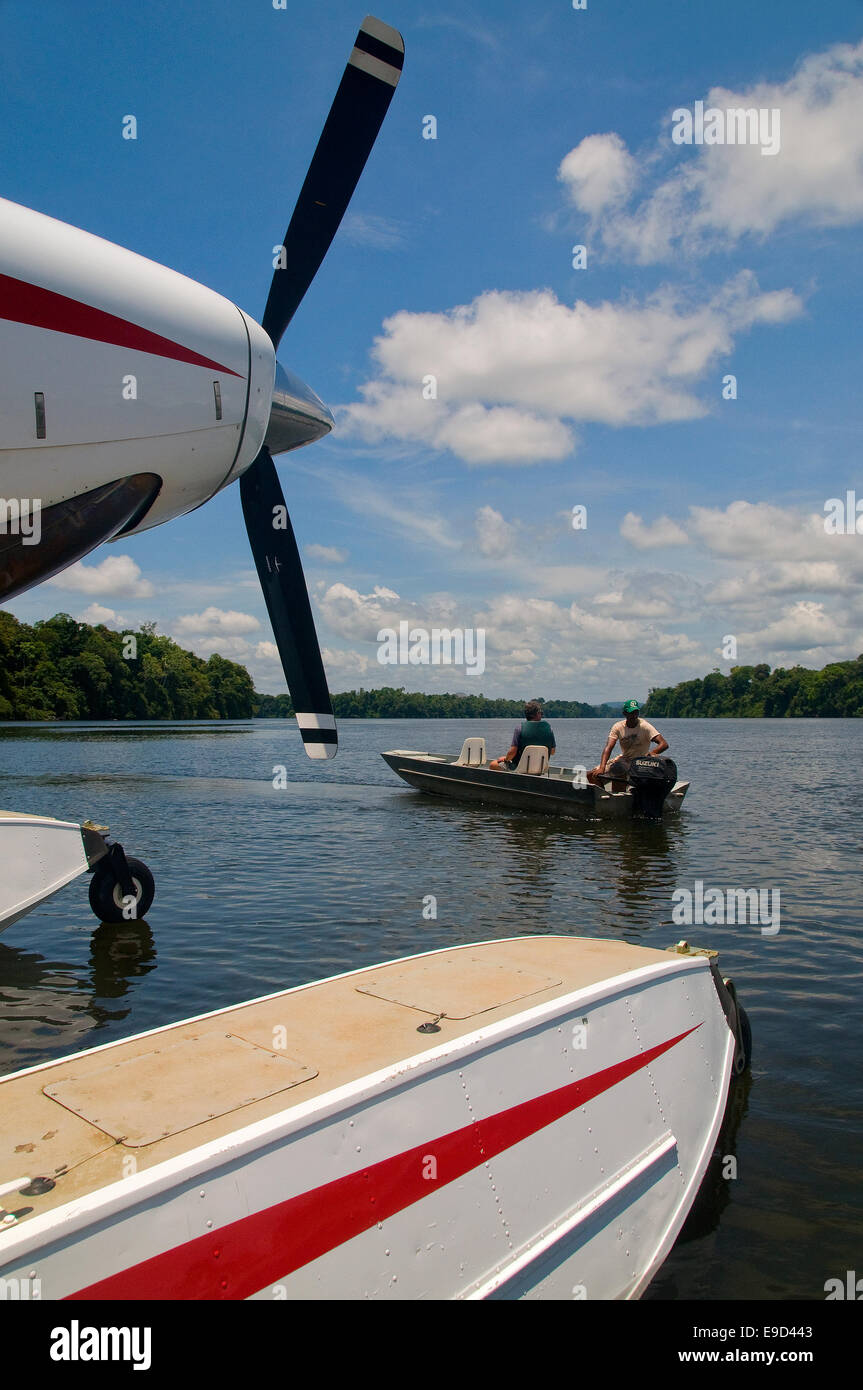 A Caravan float plane unloads gear and passengers into a small canoe on ...