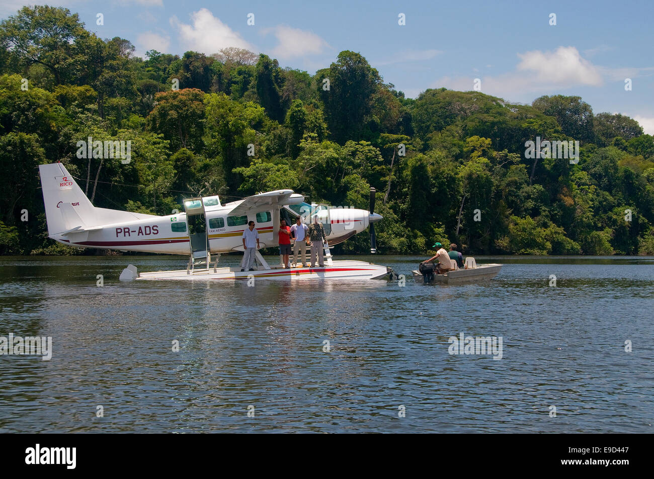 A Caravan float plane unloads gear and passengers into a small canoe on ...