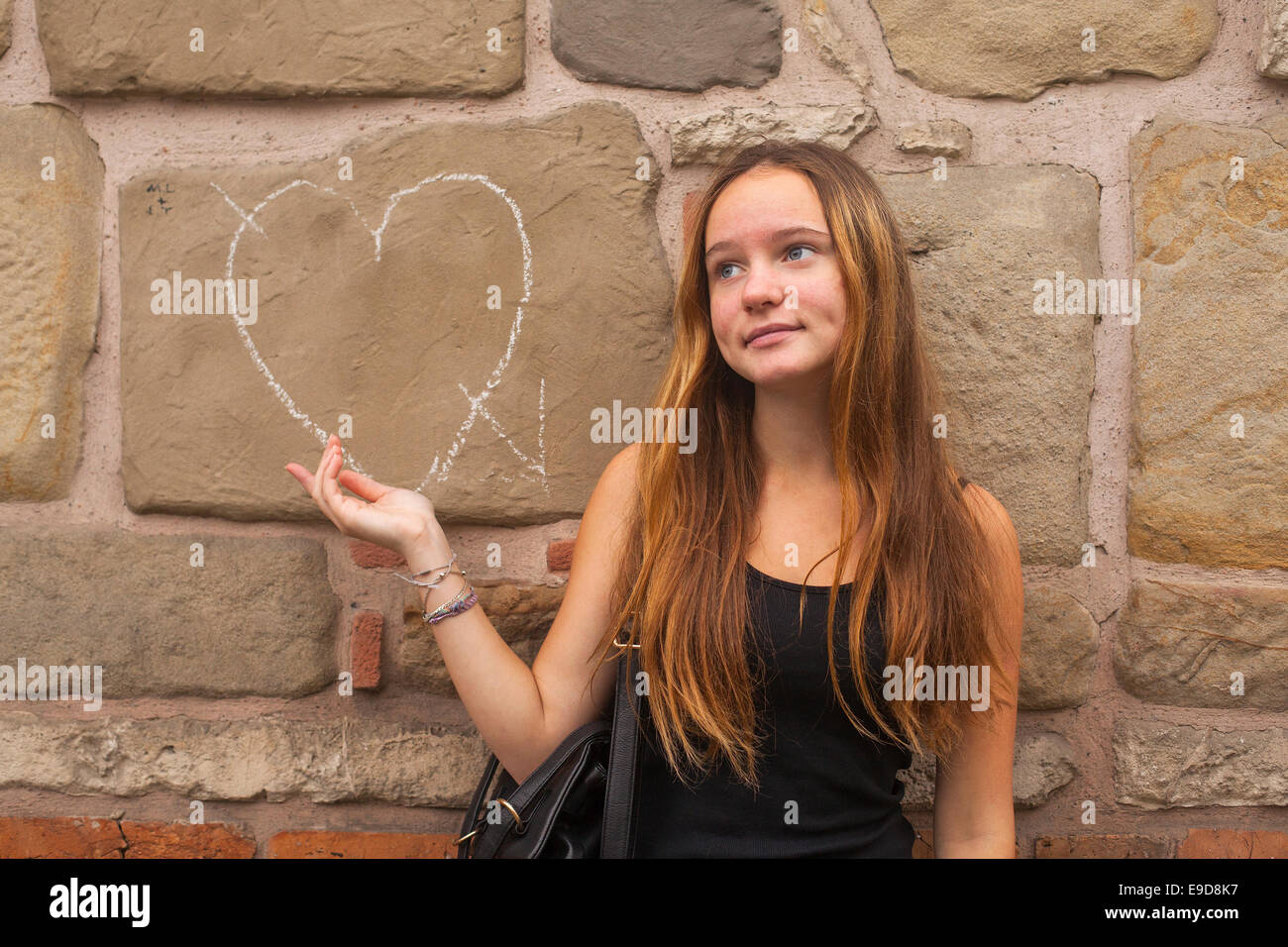 Teen girl in frustration standing against the wall with the drawn heart ...