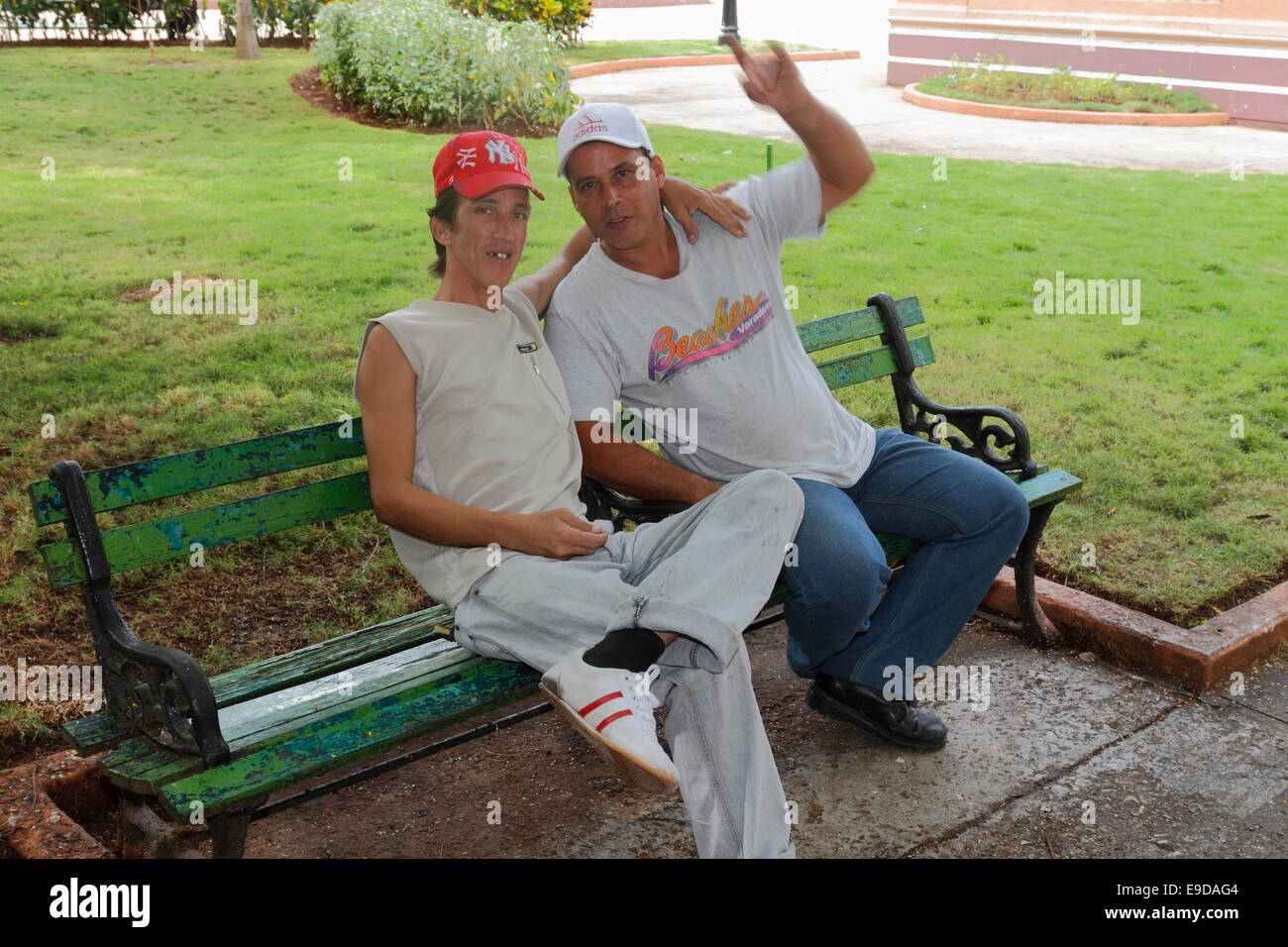 Two young Latin Cuban adult man sitting close friendly on the wooden ...
