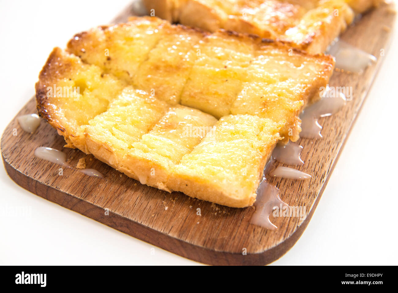 Bread toast and condensed milk on wooden plate over white background ...