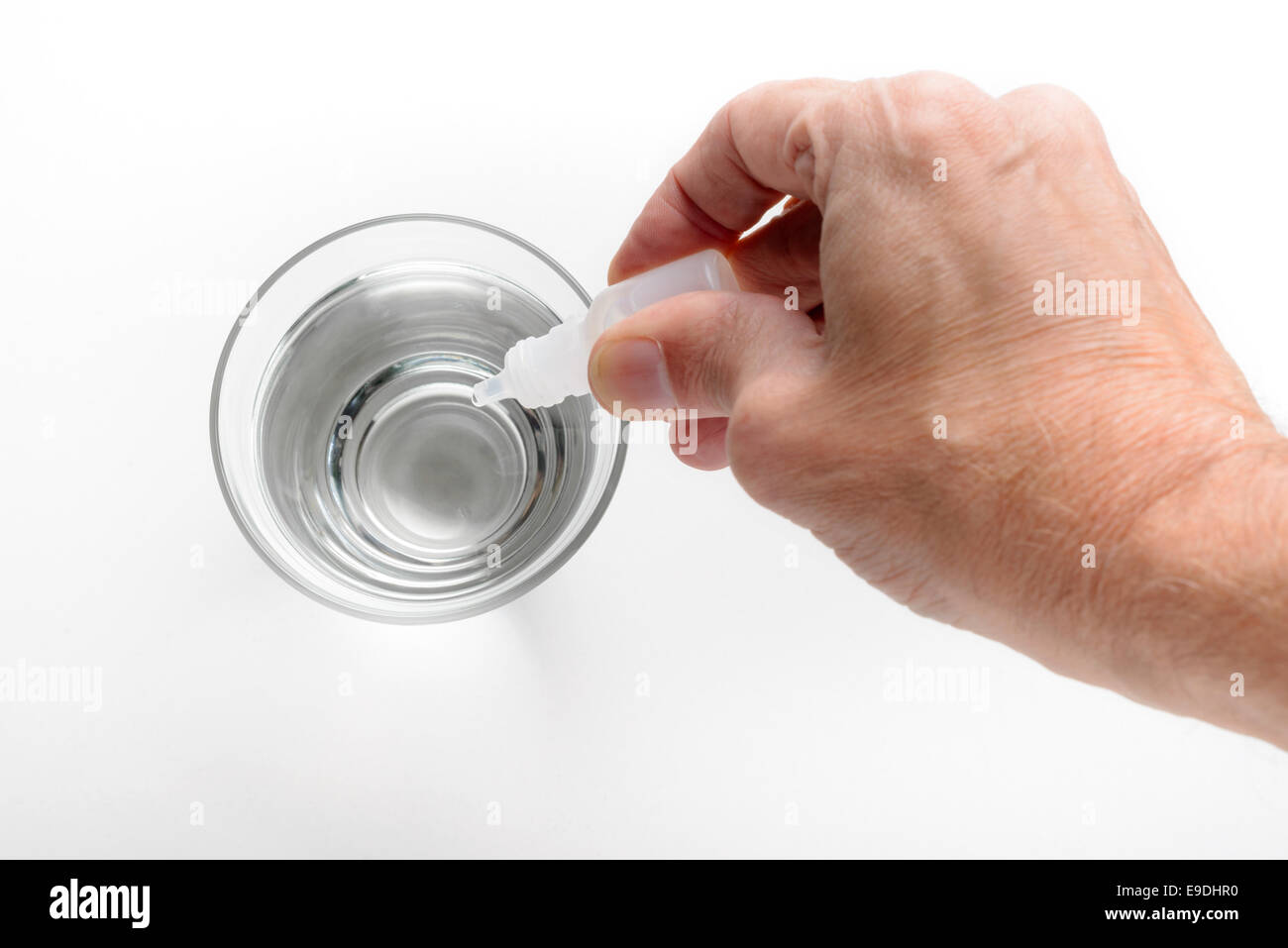 Man's hand putting drops of pharmacy in a glass of transparent water ...