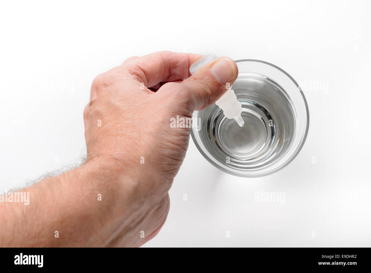 Man's hand putting drops of pharmacy in a glass of transparent water ...
