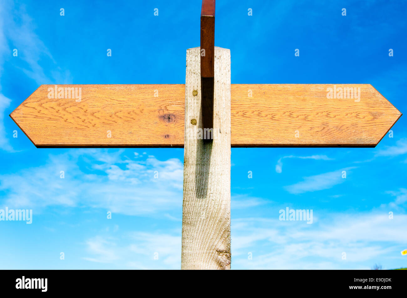 Blank wooden signpost with two arrows over clear blue sky with copy ...