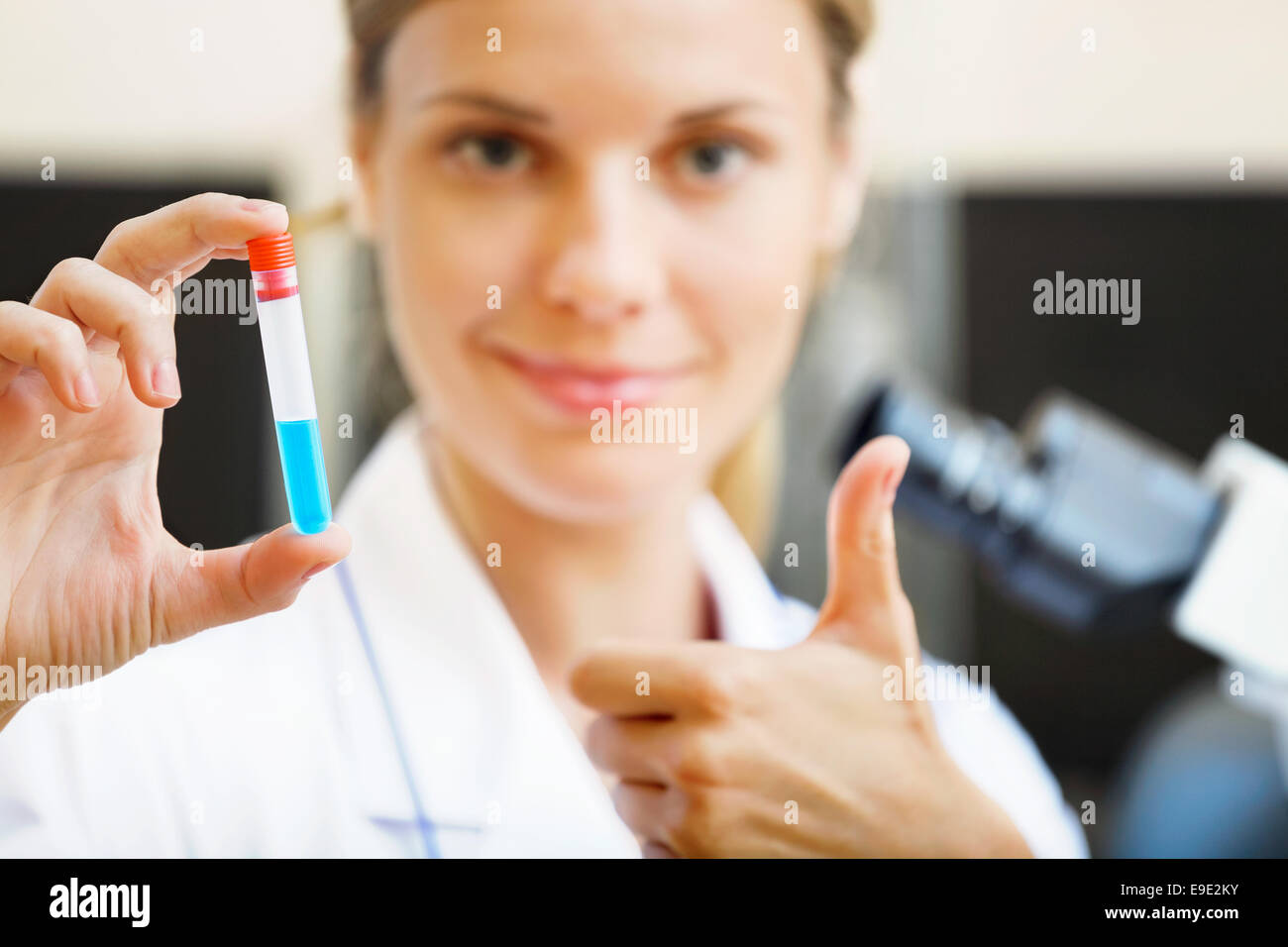 Happy young beautiful scientist holding samples with positive testing ...