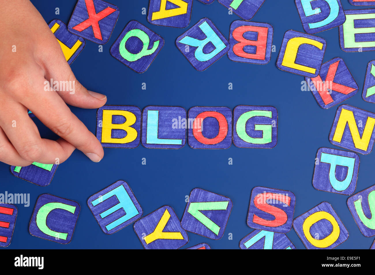 Word "Blog" spell out on blue background with woman's hand and letters ...