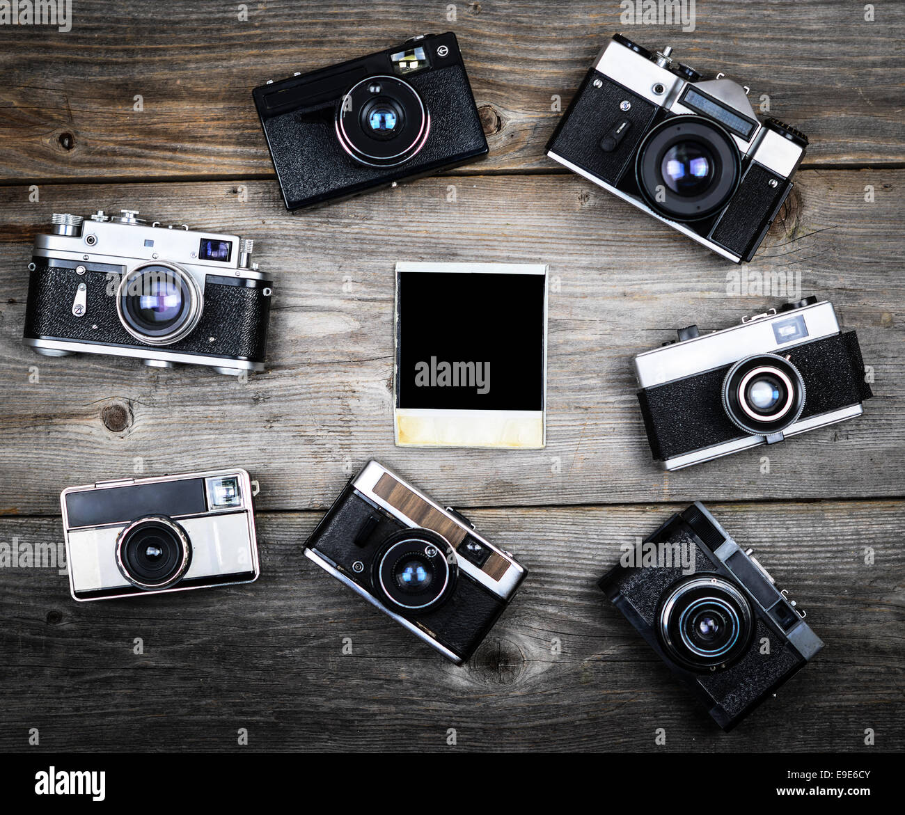 Group of vintage cameras around single blank photograph on wooden ...