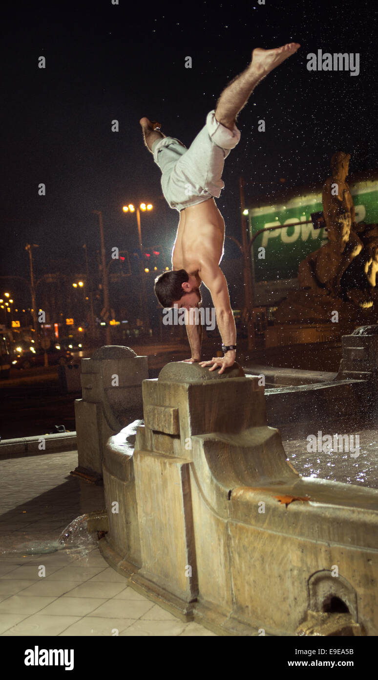 Amazing man doing sport figures in the fountain Stock Photo - Alamy