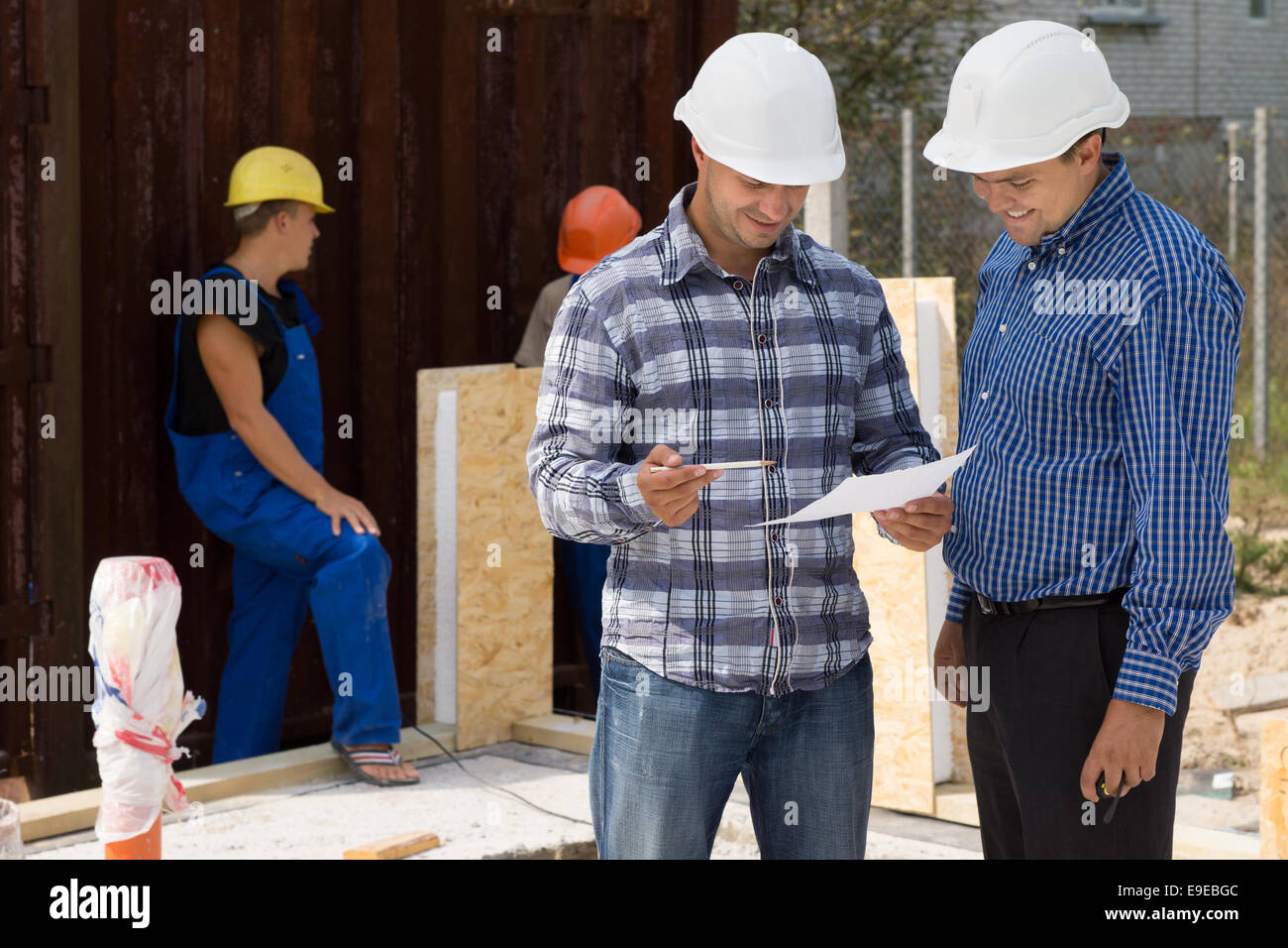 Engineer and architect wearing hardhats standing discussing paperwork ...