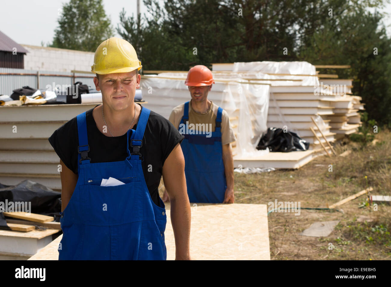 Construction workers carrying insulated wooden wall panels on a ...
