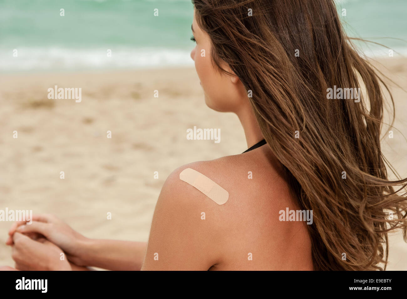 Woman at the beach with a on bandage her upper back Stock Photo - Alamy