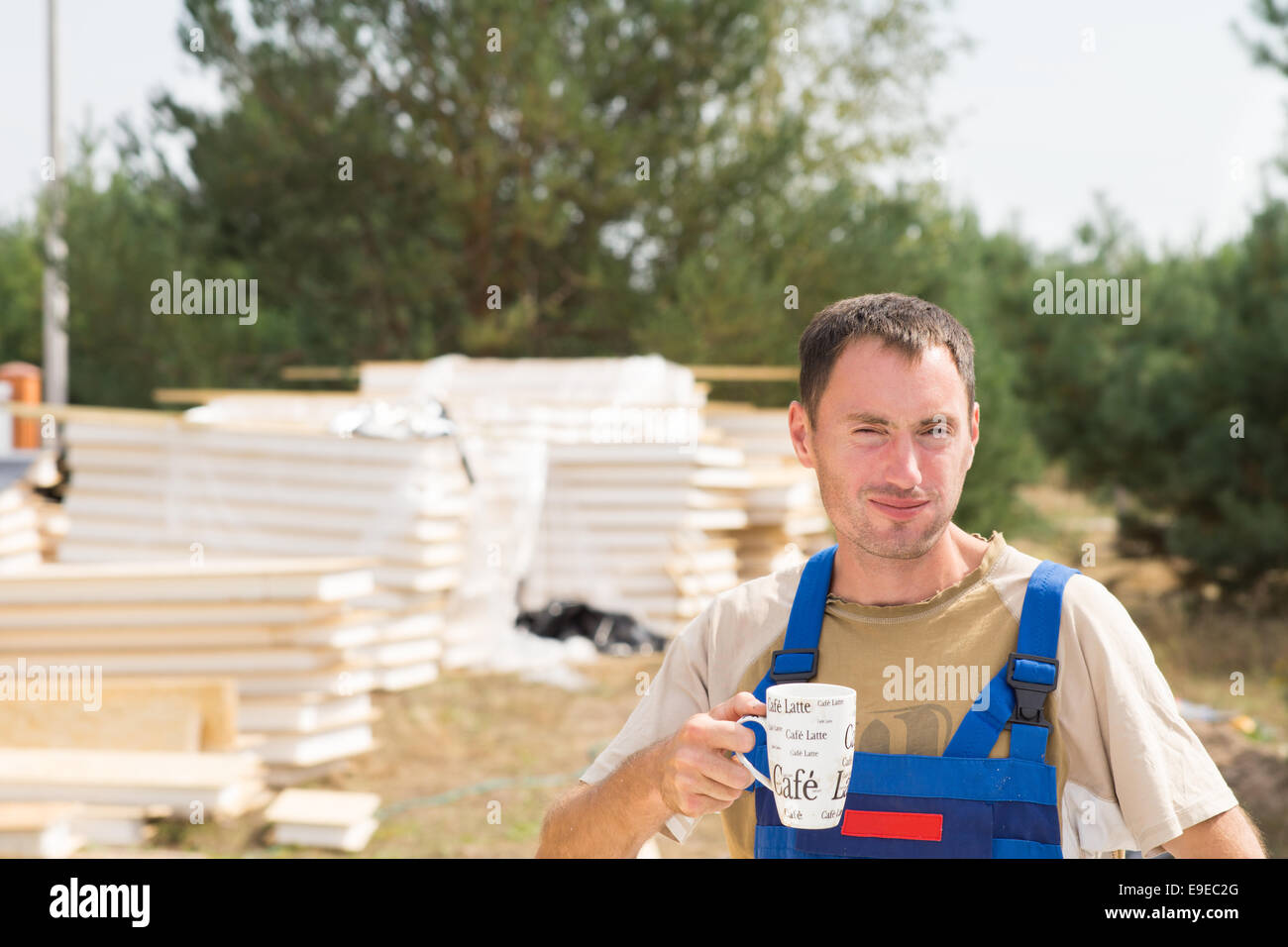 Workman taking a coffee break on a construction site standing in front ...