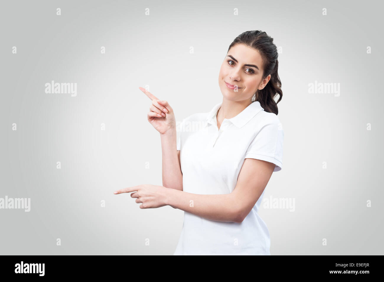 Beautiful casual woman pointing above presenting isolated on a white ...