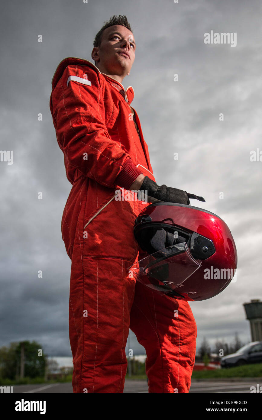 Racer posing with his arms crossed wearing red racing suit and helmet ...