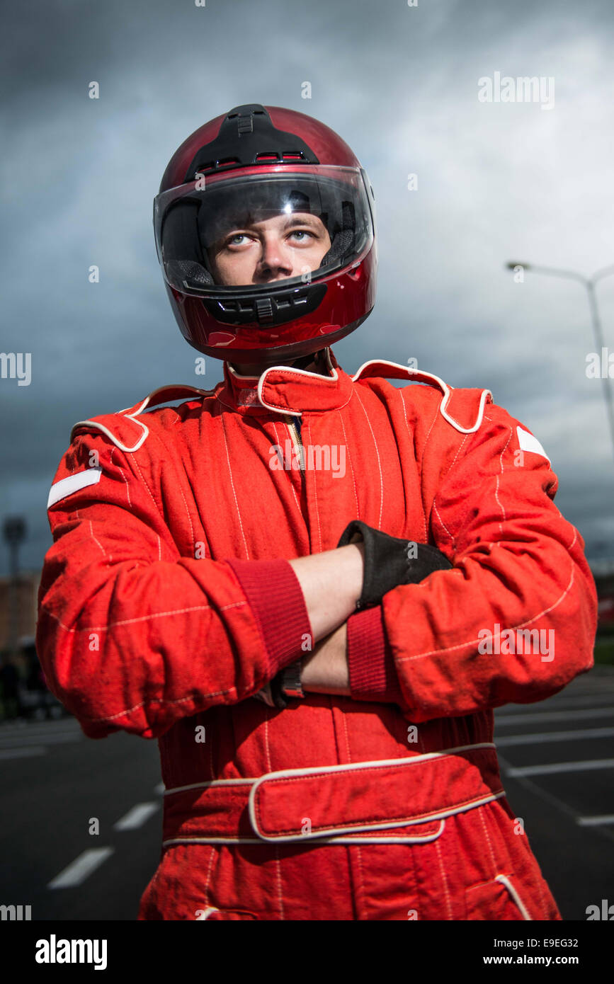 Racer posing with his arms crossed wearing red racing suit and helmet ...