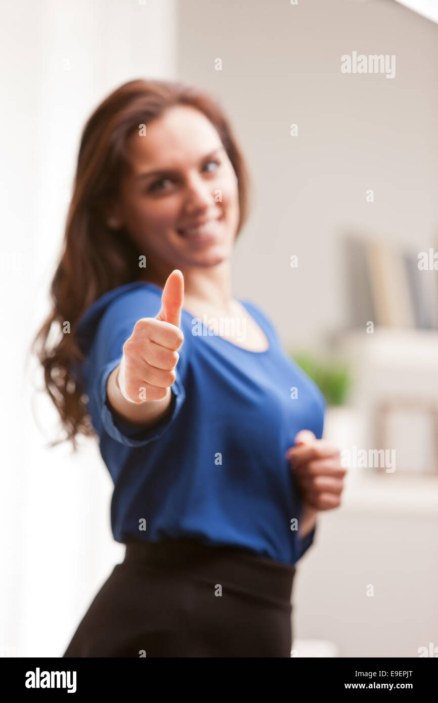 girl raising thumbs up in her living room happily Stock Photo - Alamy