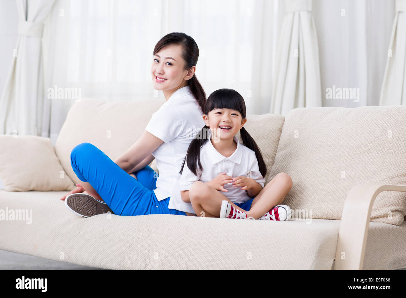 Mother and daughter sitting back to back Stock Photo - Alamy