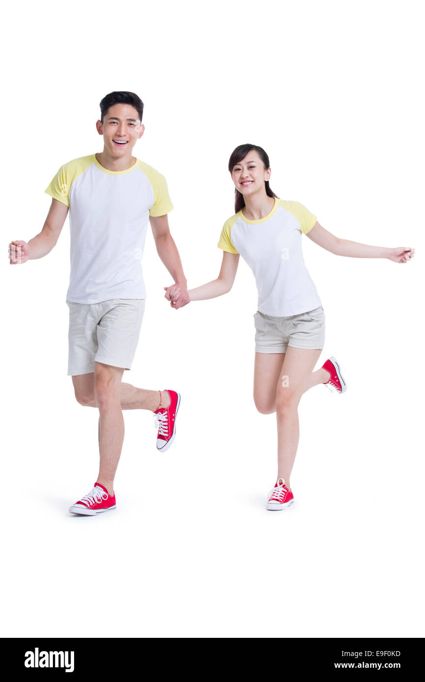 Happy young couple holding hands running Stock Photo - Alamy