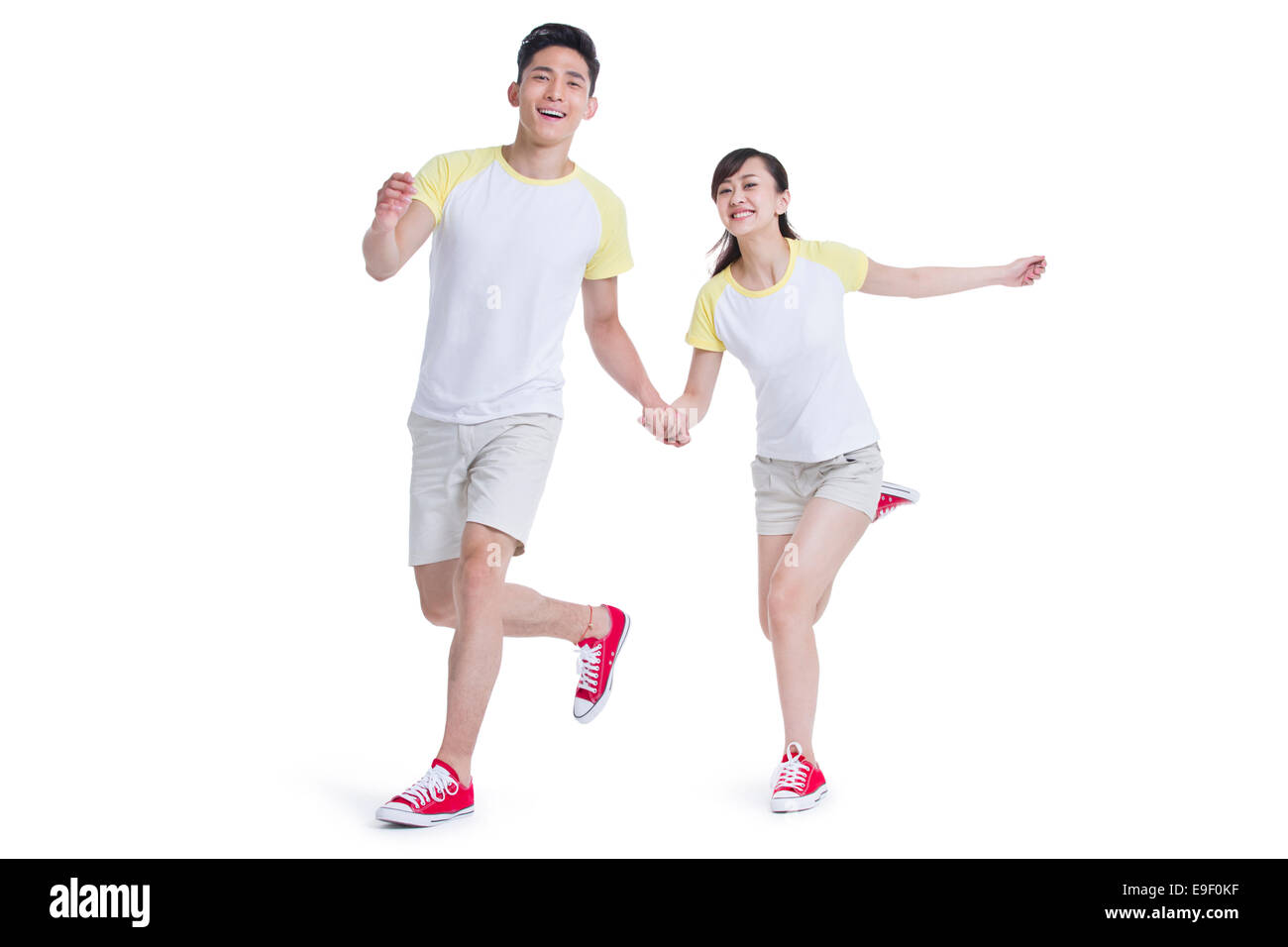 Happy young couple holding hands running Stock Photo - Alamy