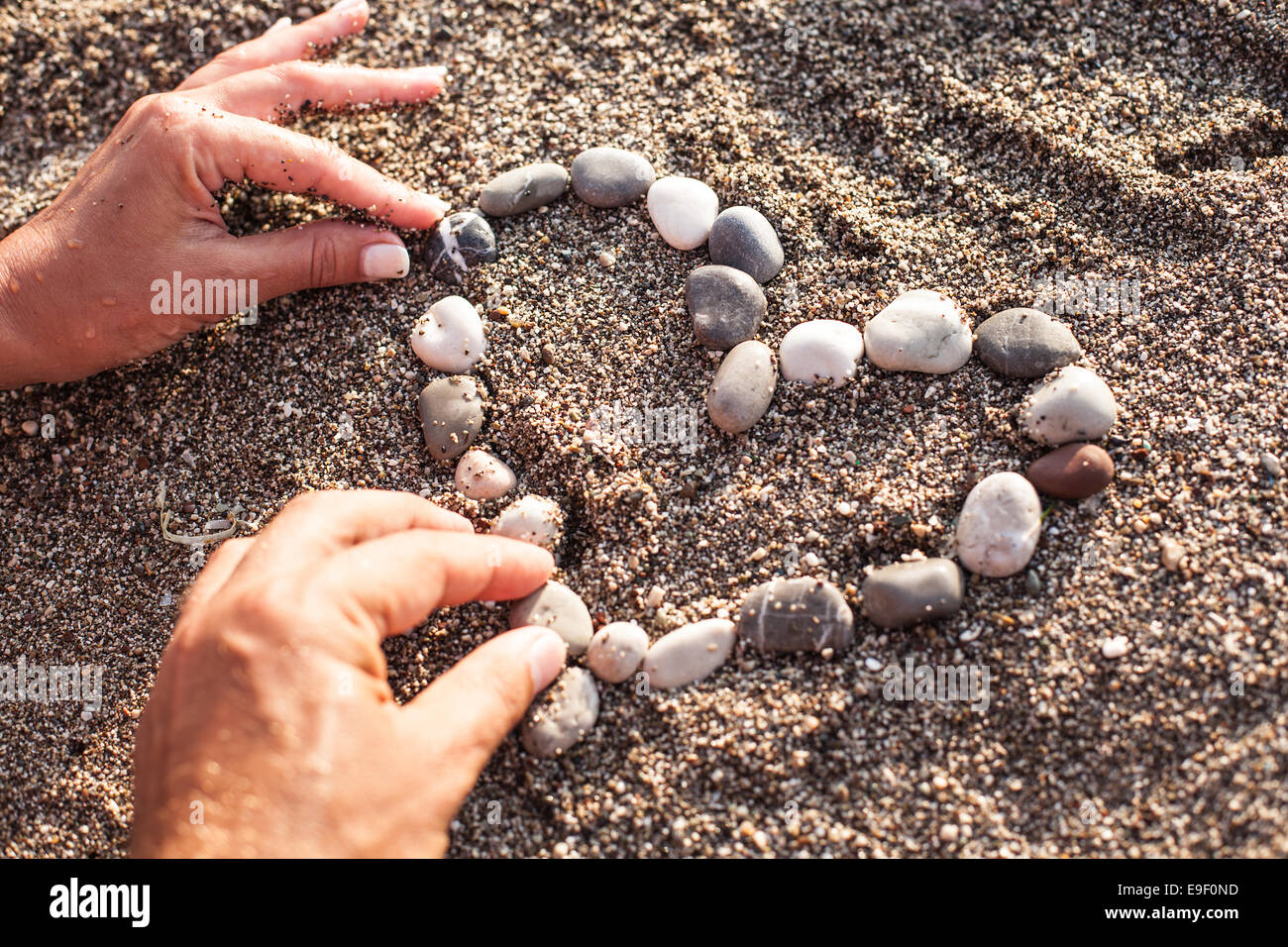 Heart symbol is made of marine shingles by man and woman Stock Photo ...
