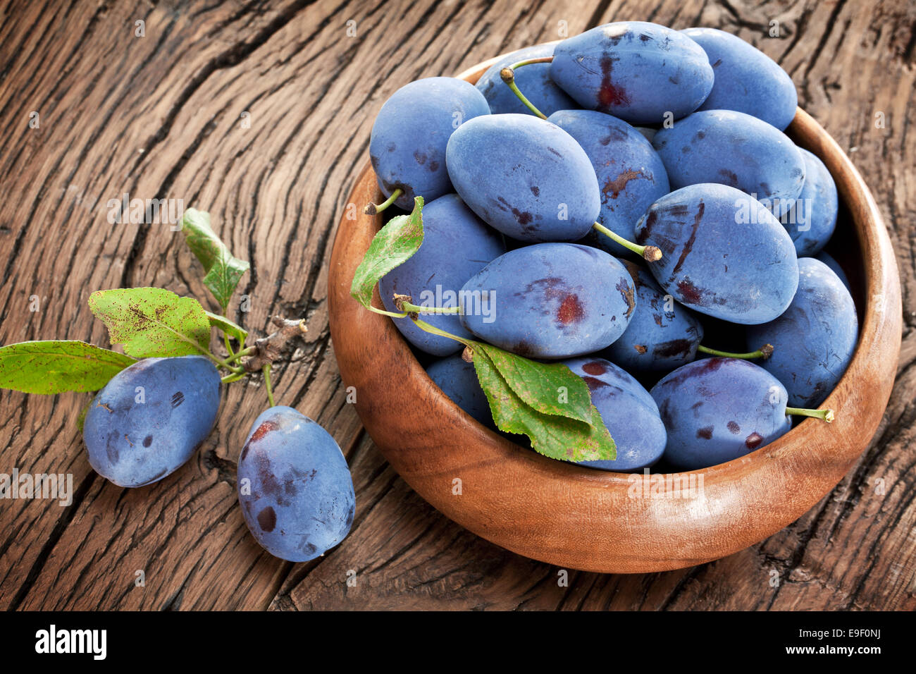 Plums on an old wooden table in the garden Stock Photo - Alamy