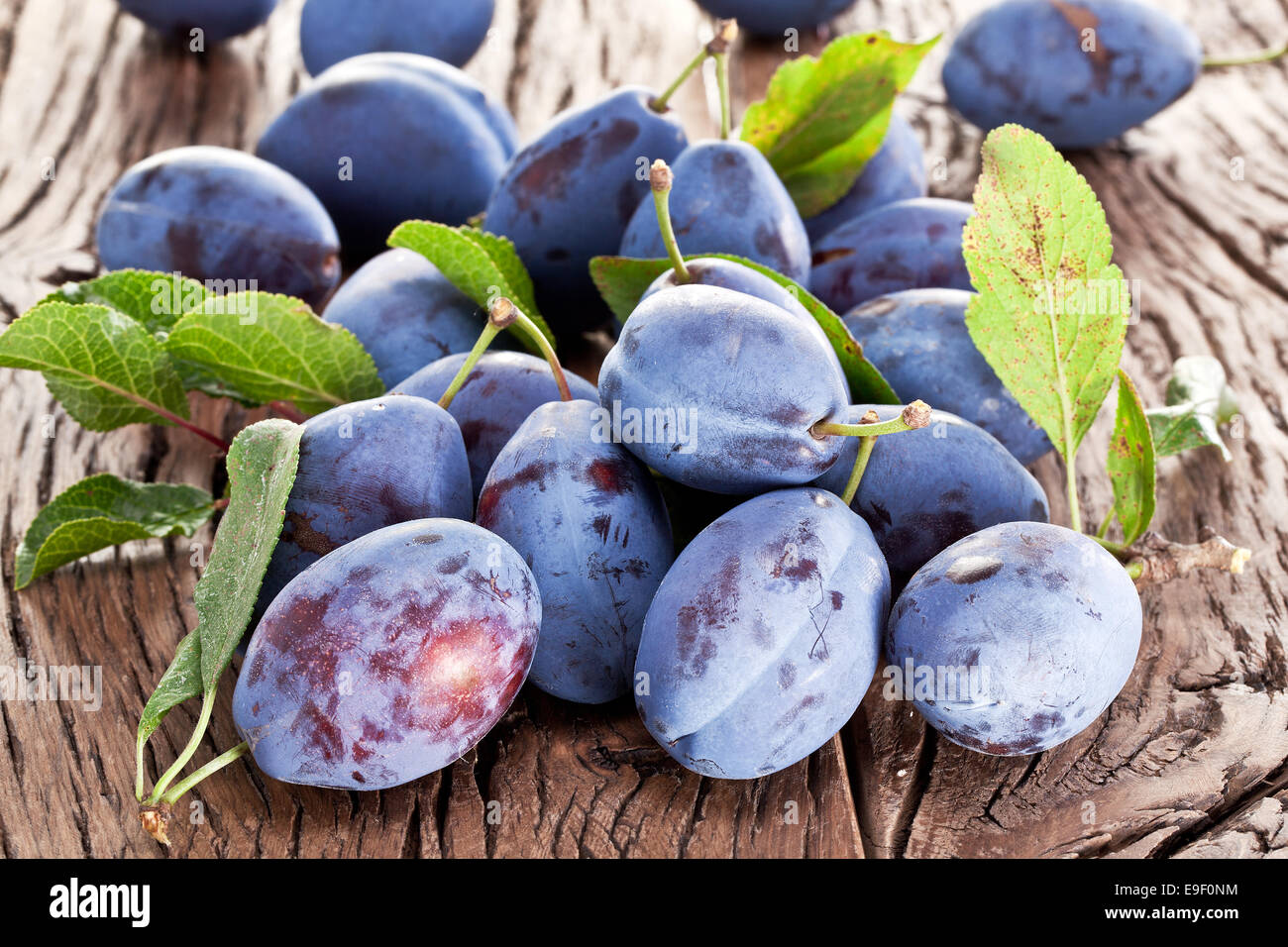Plums on an old wooden table in the garden Stock Photo - Alamy