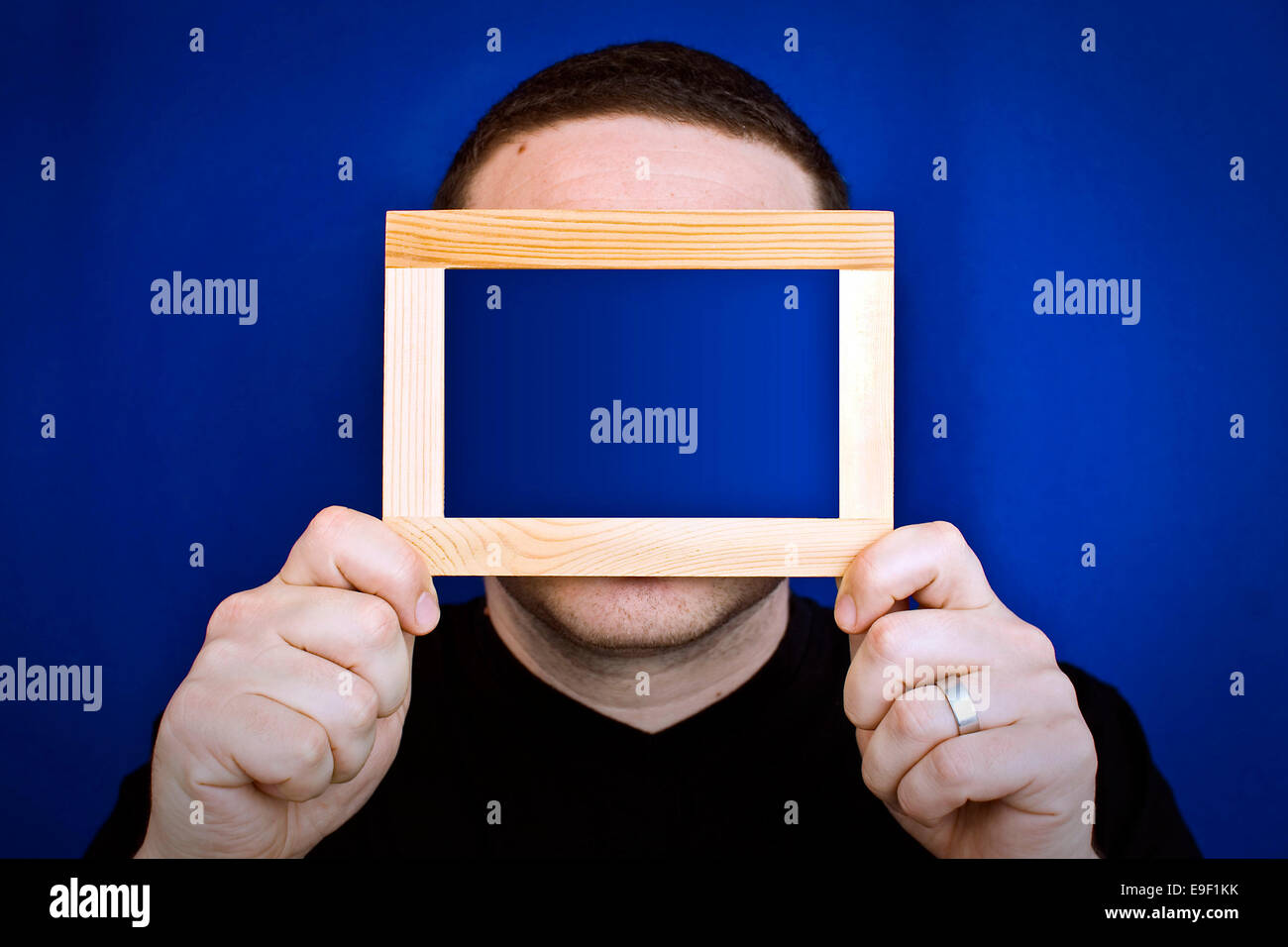 a man holds up a picture frame with a blank space where his face should ...