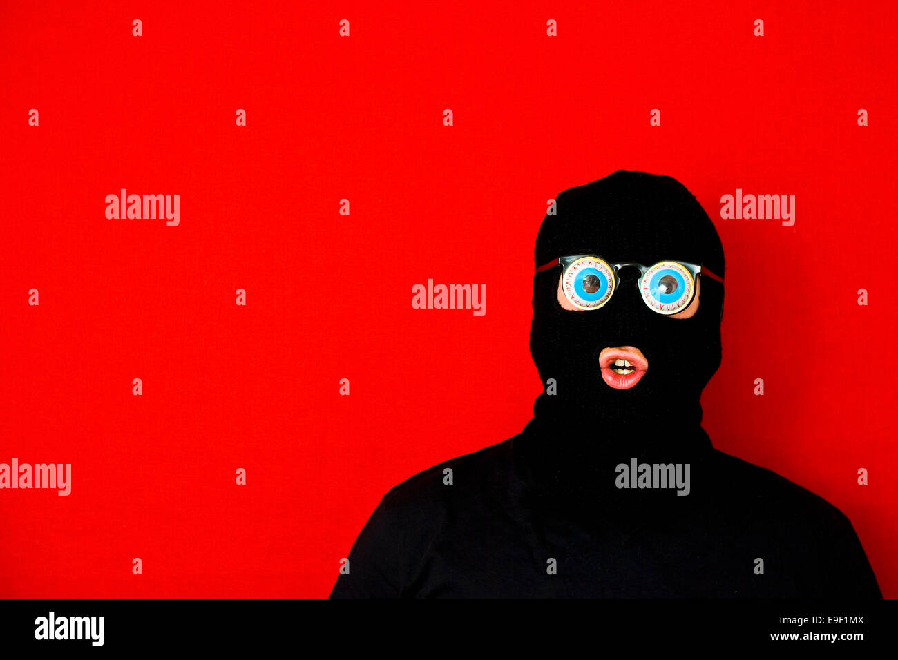 a man in a balaclava against a red background with silly comedy eye ...