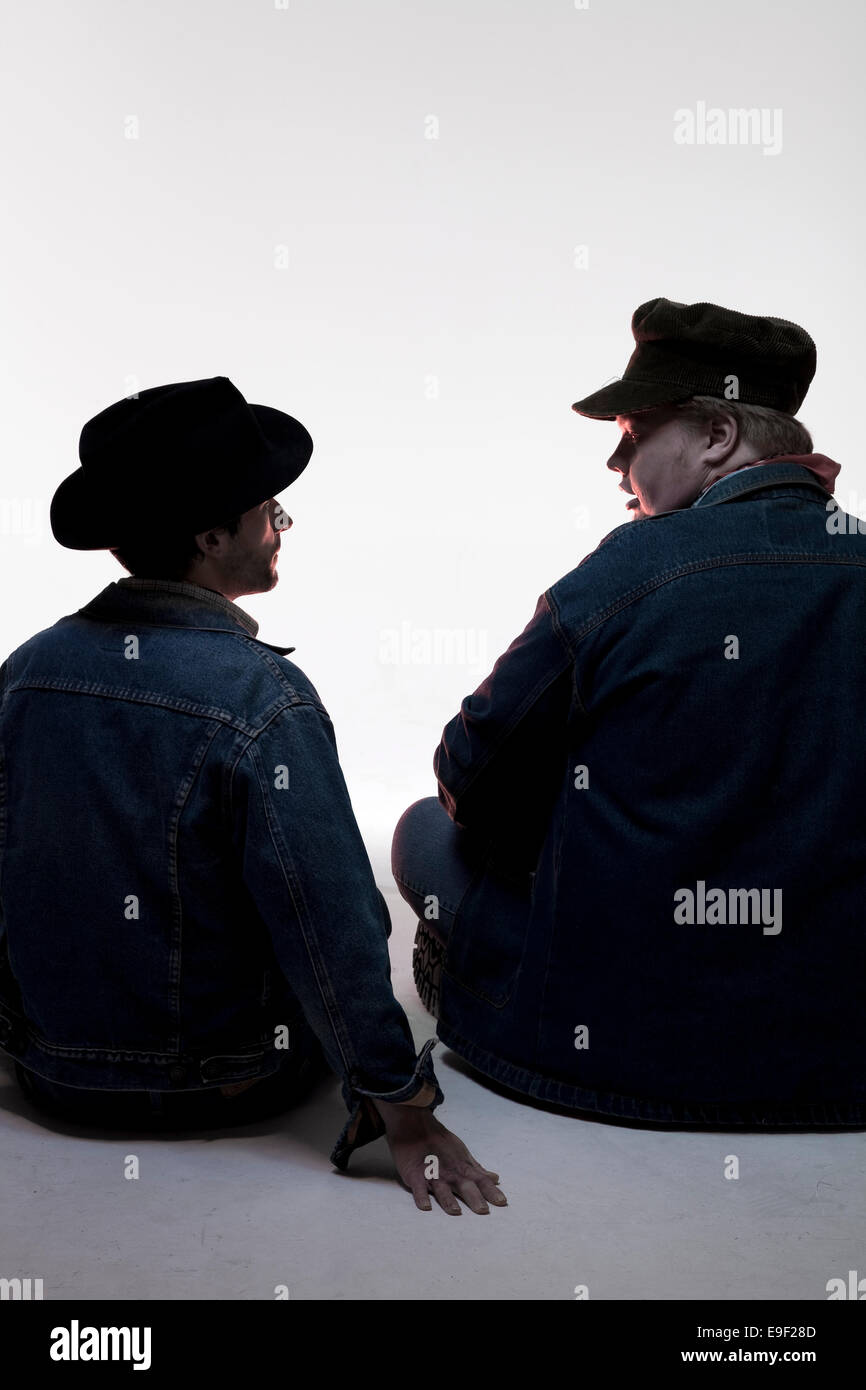 two men sitting and talking in the cowboy wild west era acting out ...