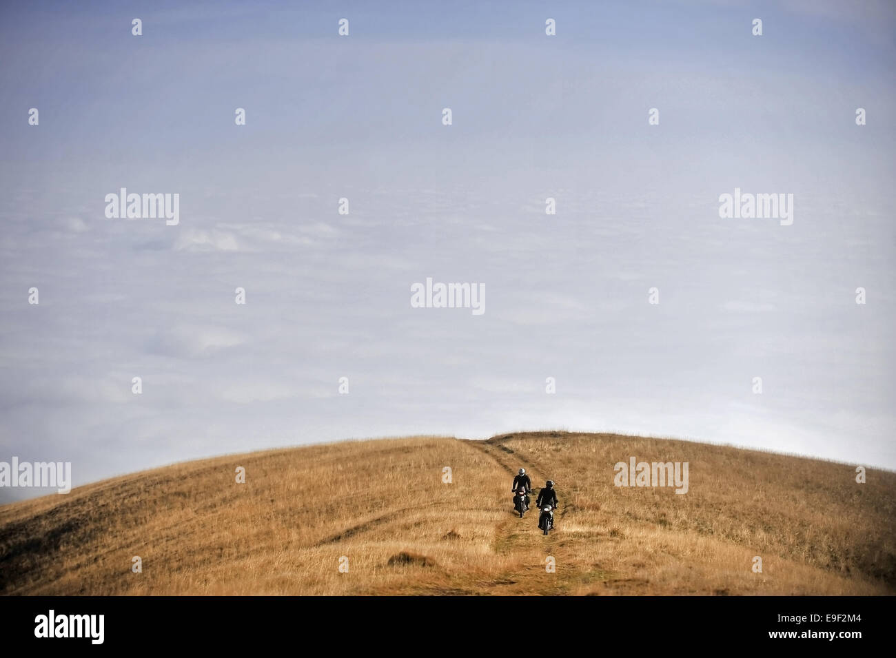 Two motorcycles riding on a mountain plateau above the clouds Stock ...