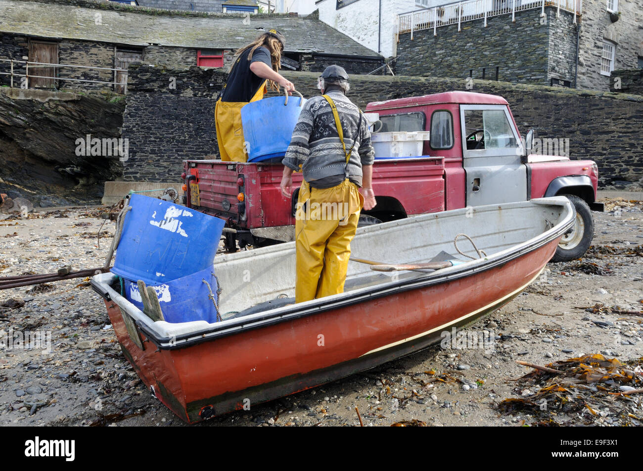 Cornish fishermen moving buckets of crab from a small boat to an old ...