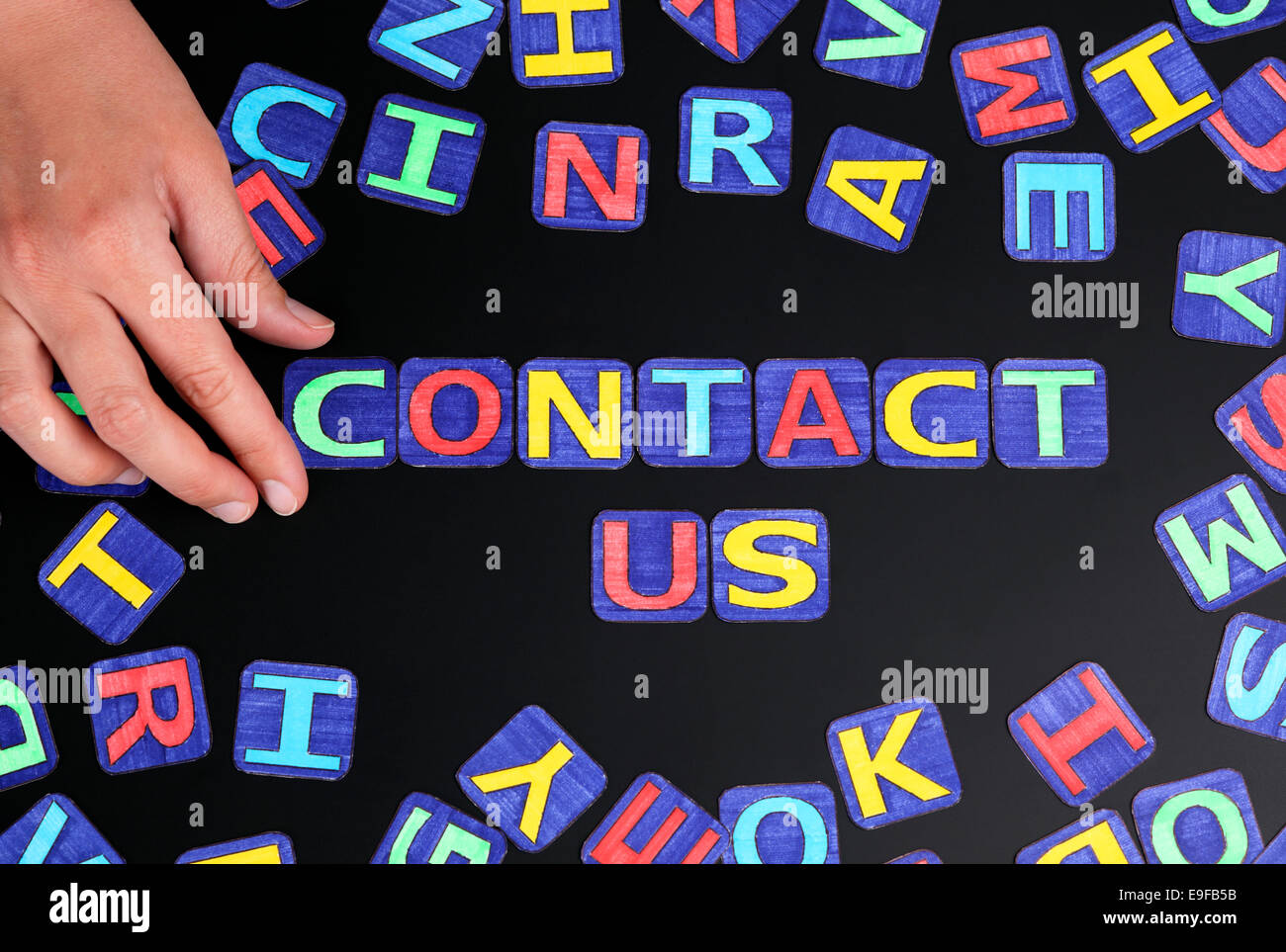 Words "Contact us" spell out on black background with woman's hand and ...