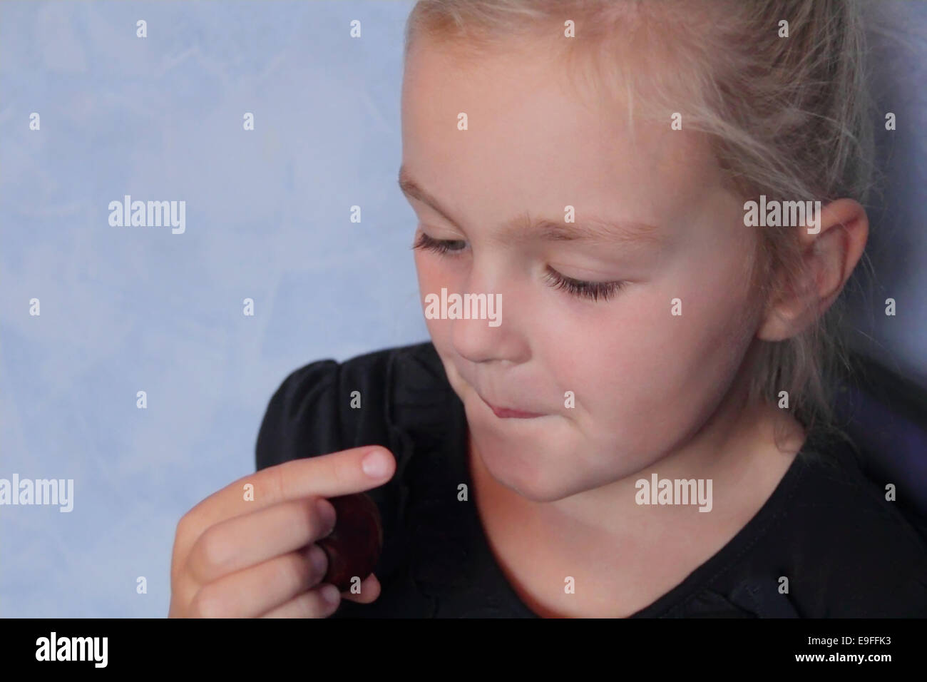 Beautiful small girl eating sweetmeat Stock Photo - Alamy