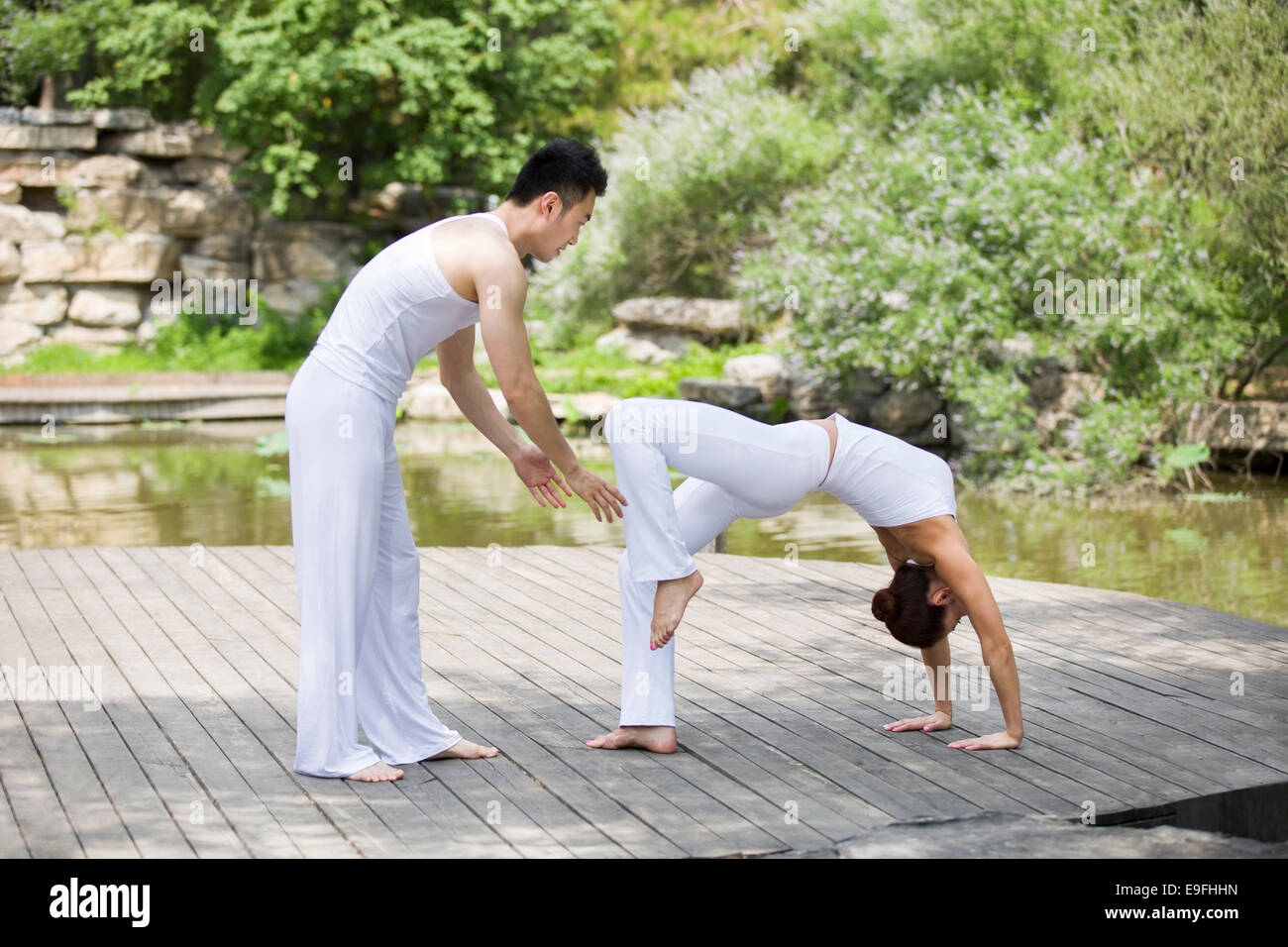 Yoga instructor helping woman with pose Stock Photo - Alamy