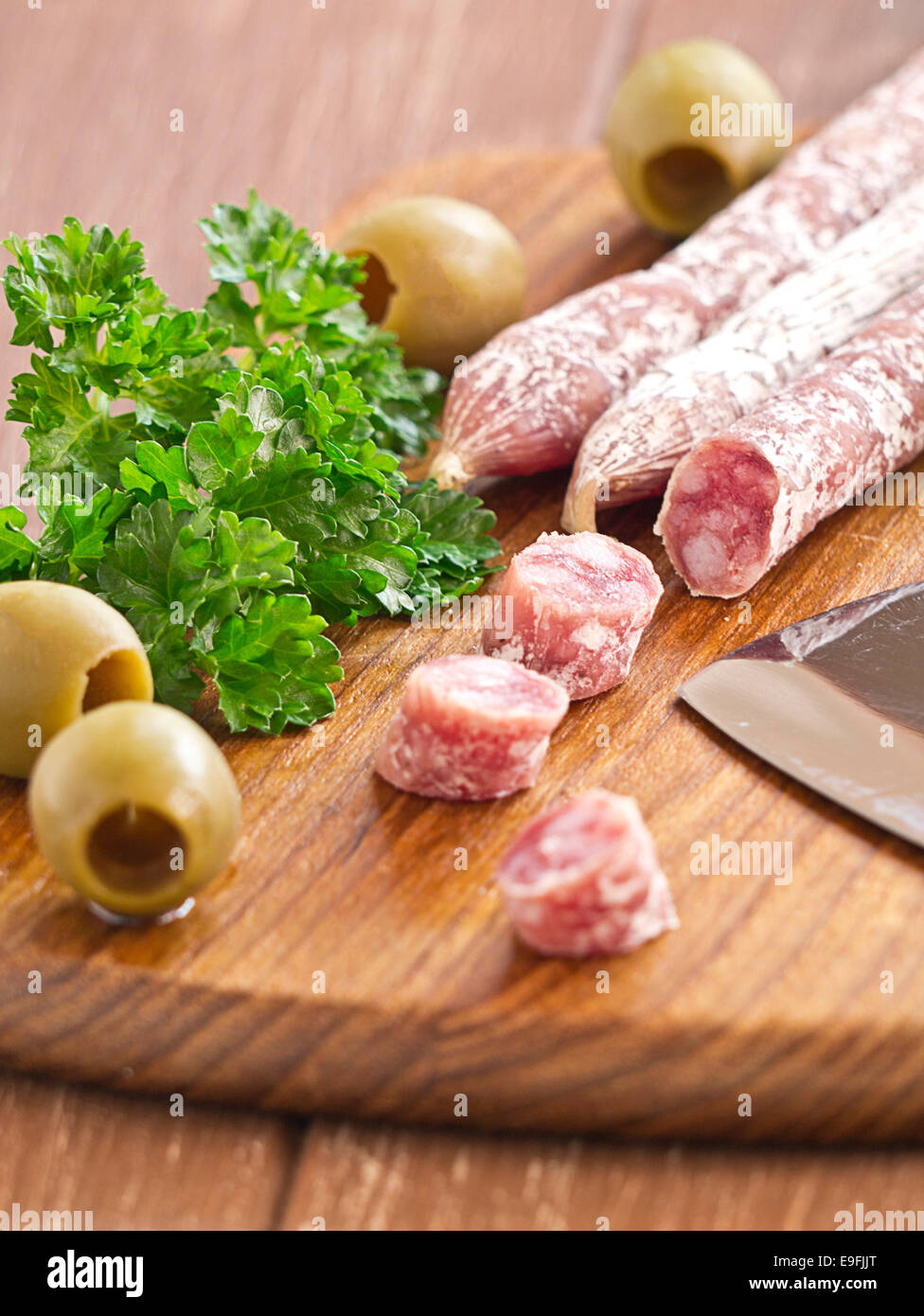 Salami on on a wood board with olives Stock Photo - Alamy