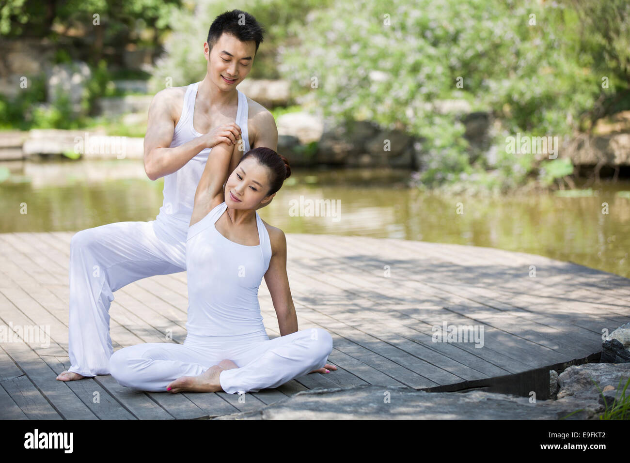 Yoga instructor helping woman with pose Stock Photo - Alamy