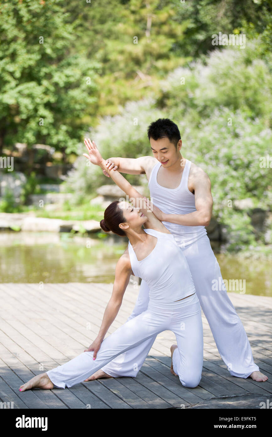 Yoga instructor helping woman with pose Stock Photo - Alamy