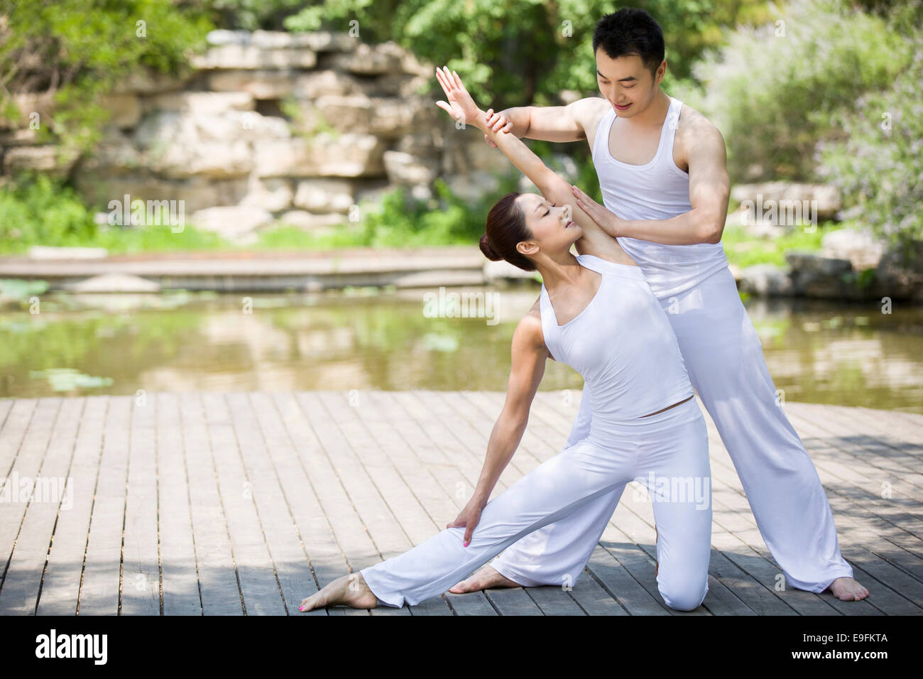 Yoga instructor helping woman with pose Stock Photo - Alamy