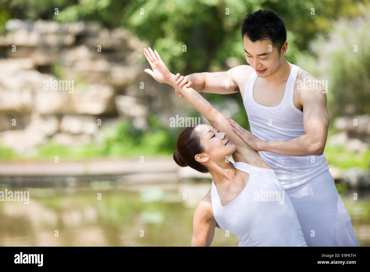 Yoga instructor helping woman with pose Stock Photo - Alamy