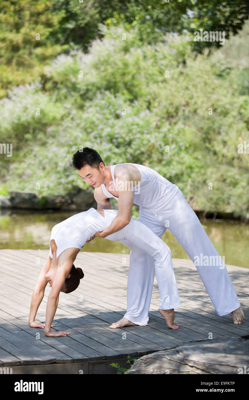 Yoga instructor helping woman with pose Stock Photo - Alamy