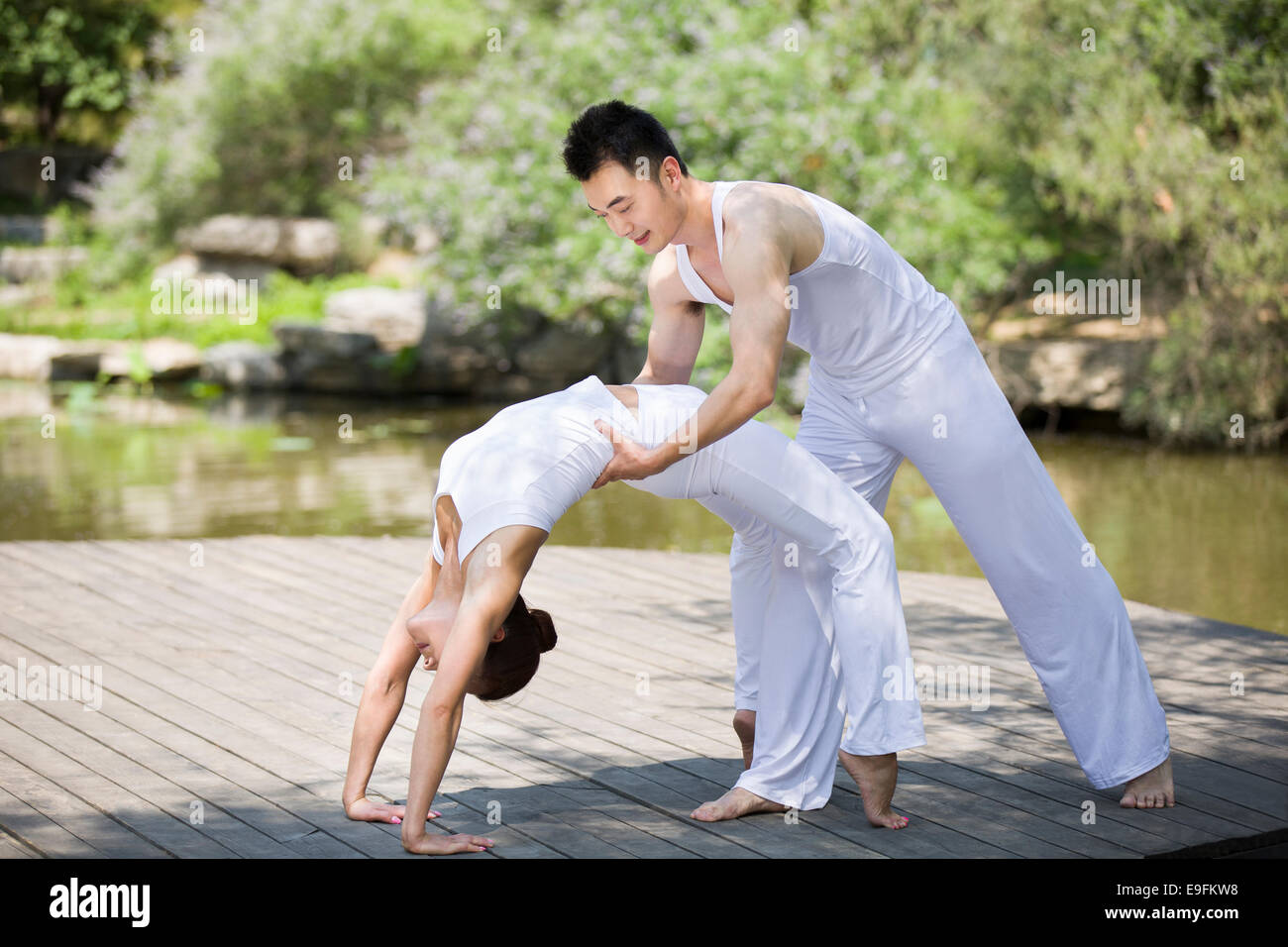 Yoga instructor helping woman with pose Stock Photo - Alamy