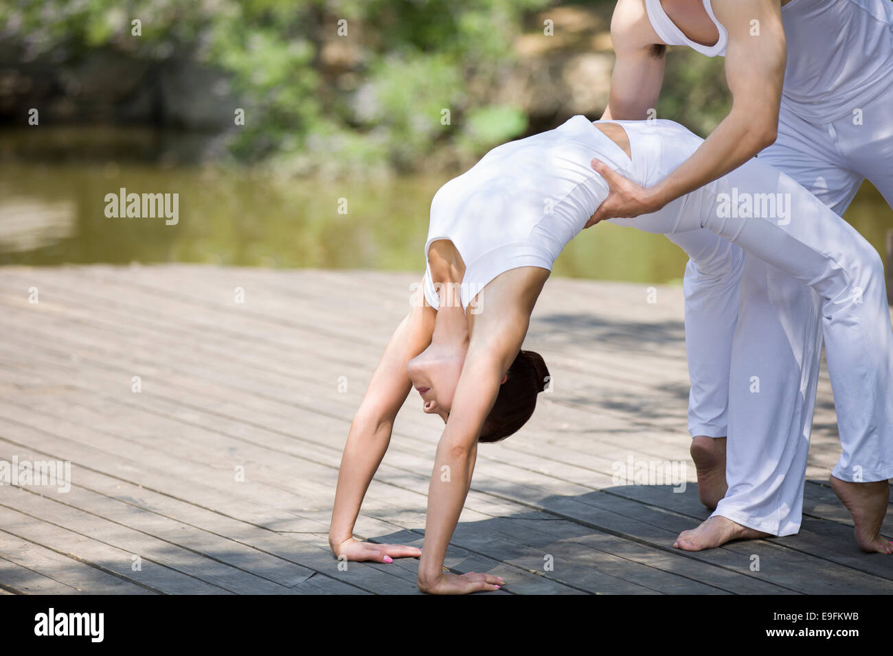 Yoga instructor helping woman with pose Stock Photo - Alamy