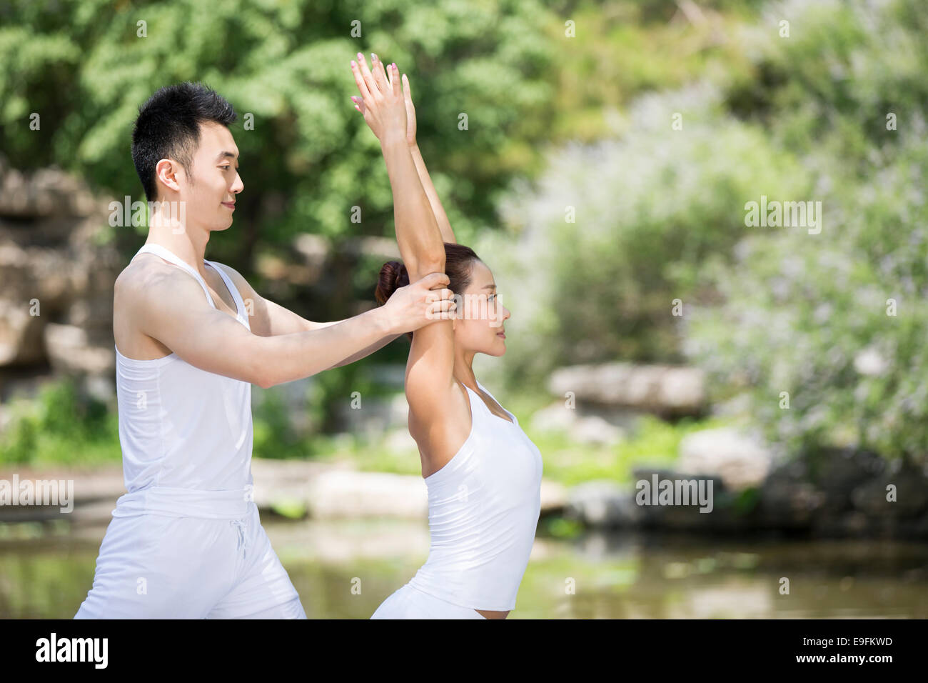 Yoga instructor helping woman with pose Stock Photo - Alamy